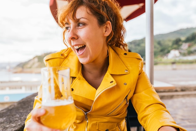 Mujer Caucásica Con Una Chaqueta Amarilla Bebiendo Un Vaso De Cerveza Y