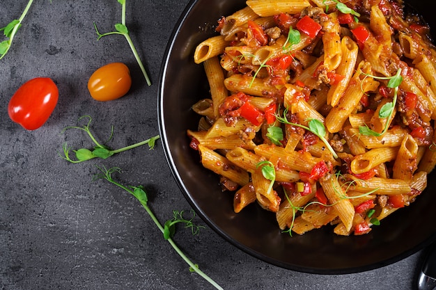 Macarrão penne em molho de tomate com carne, tomate decorado com brotos ... Macarrão penne em molho de tomate com carne, tomate decorado com brotos ...