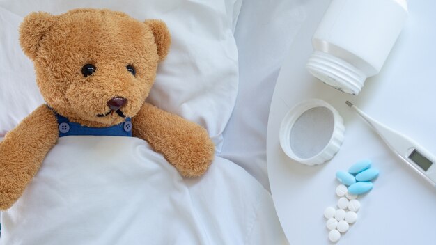 Urso De Pelúcia Deitado Doente Na Cama Com Termômetro E Gesso Foto Premium