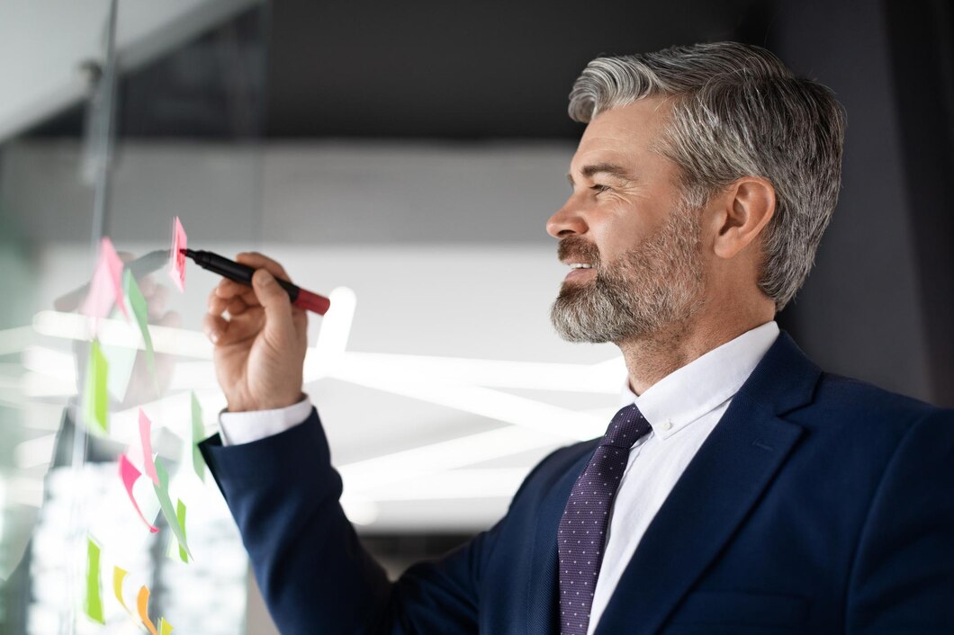 Empresário de meia-idade escrevendo notas em adesivos na parede de ... Empresário de meia-idade escrevendo notas em adesivos na parede de ...