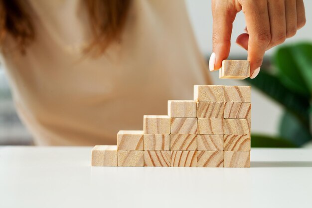 Mano de mujer arreglando el apilamiento de bloques de madera como ... Mano de mujer arreglando el apilamiento de bloques de madera como ...