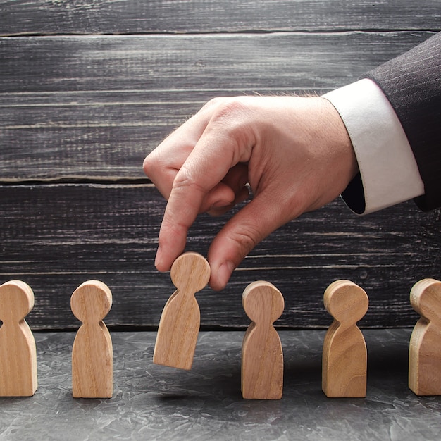 Premium Photo | Hand of a businessman takes a wooden figure of a man ... Premium Photo | Hand of a businessman takes a wooden figure of a man ...