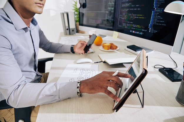 Premium Photo | Serious software developer checking data on digital tablet , smartphone and both ...