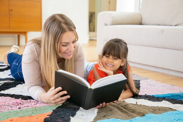 Jolie Mère Allongée Sur Un Tapis Avec Sa Fille Et Son Livre De Lecture