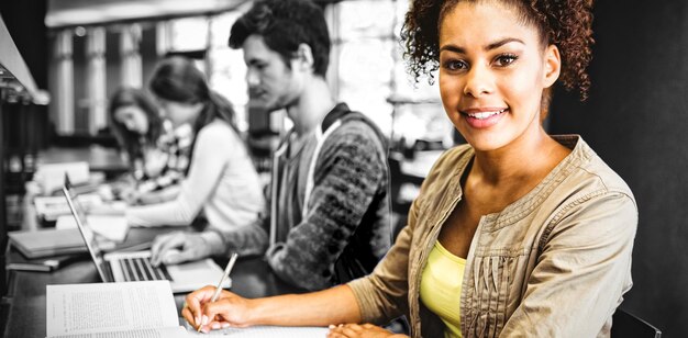 Étudiant Regardant La Caméra Tout En étudiant Avec Ses Camarades De