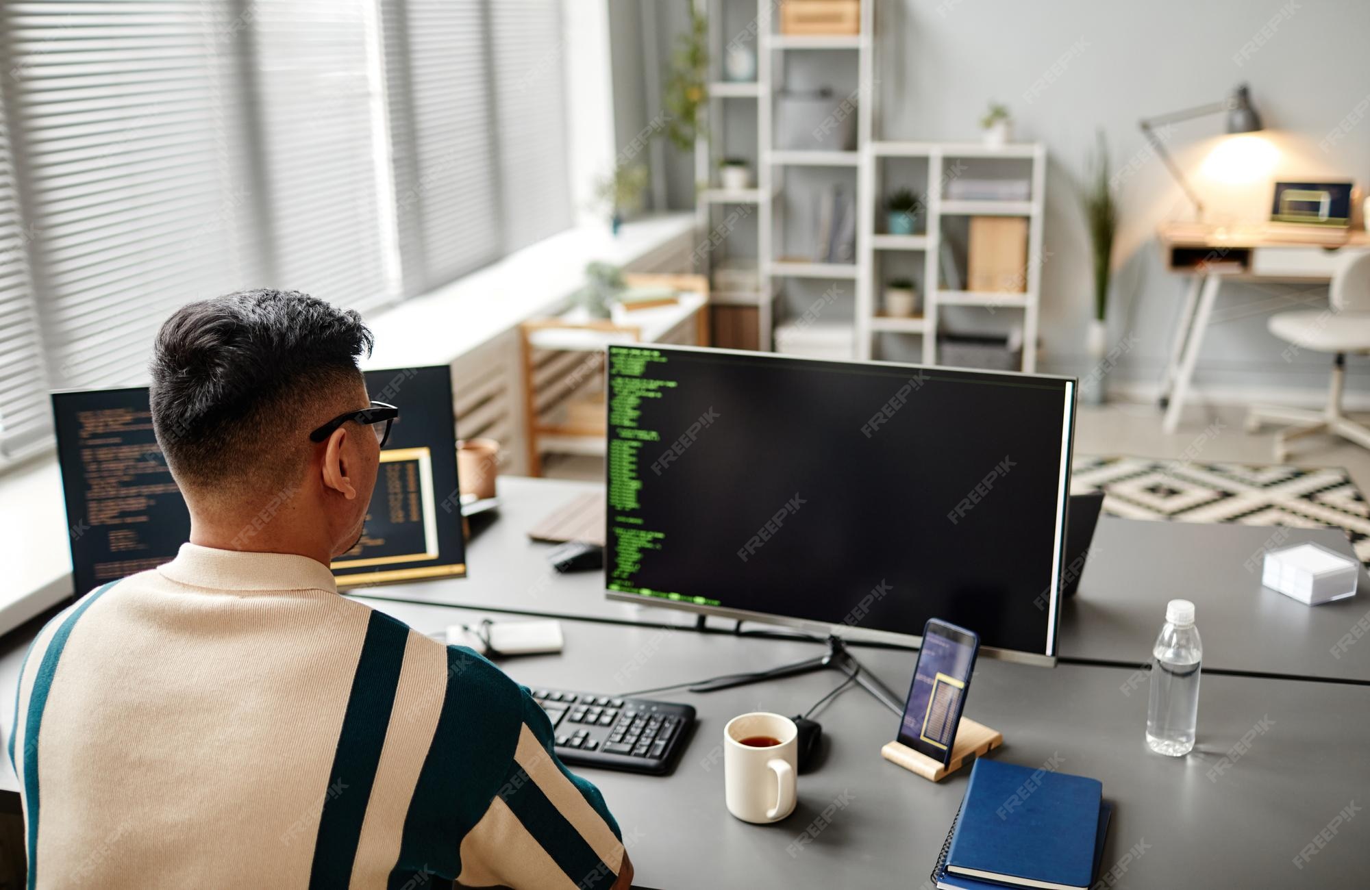Premium Photo | Back view of male it developer typing on keyboard with programming code on ...