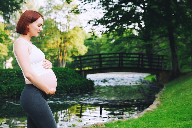 Premium Photo Beautiful Pregnant Woman Holds Hands On Belly On Nature