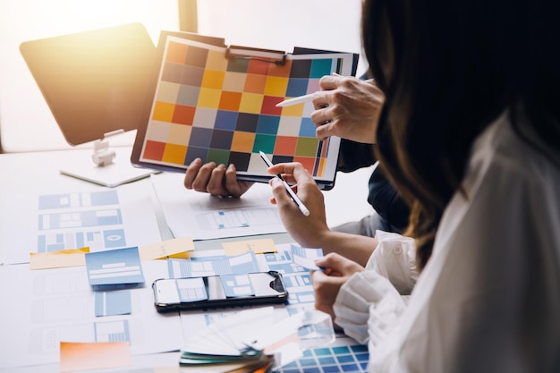 Ux 개발자 및 Ui 디자이너가 최신 사무실에서 고객 브리프 및 색상 코드를 사용하여 테이블의 모바일 앱 인터페이스 와이어프레임 디자인에 대해 브레인스토밍하는 닫기