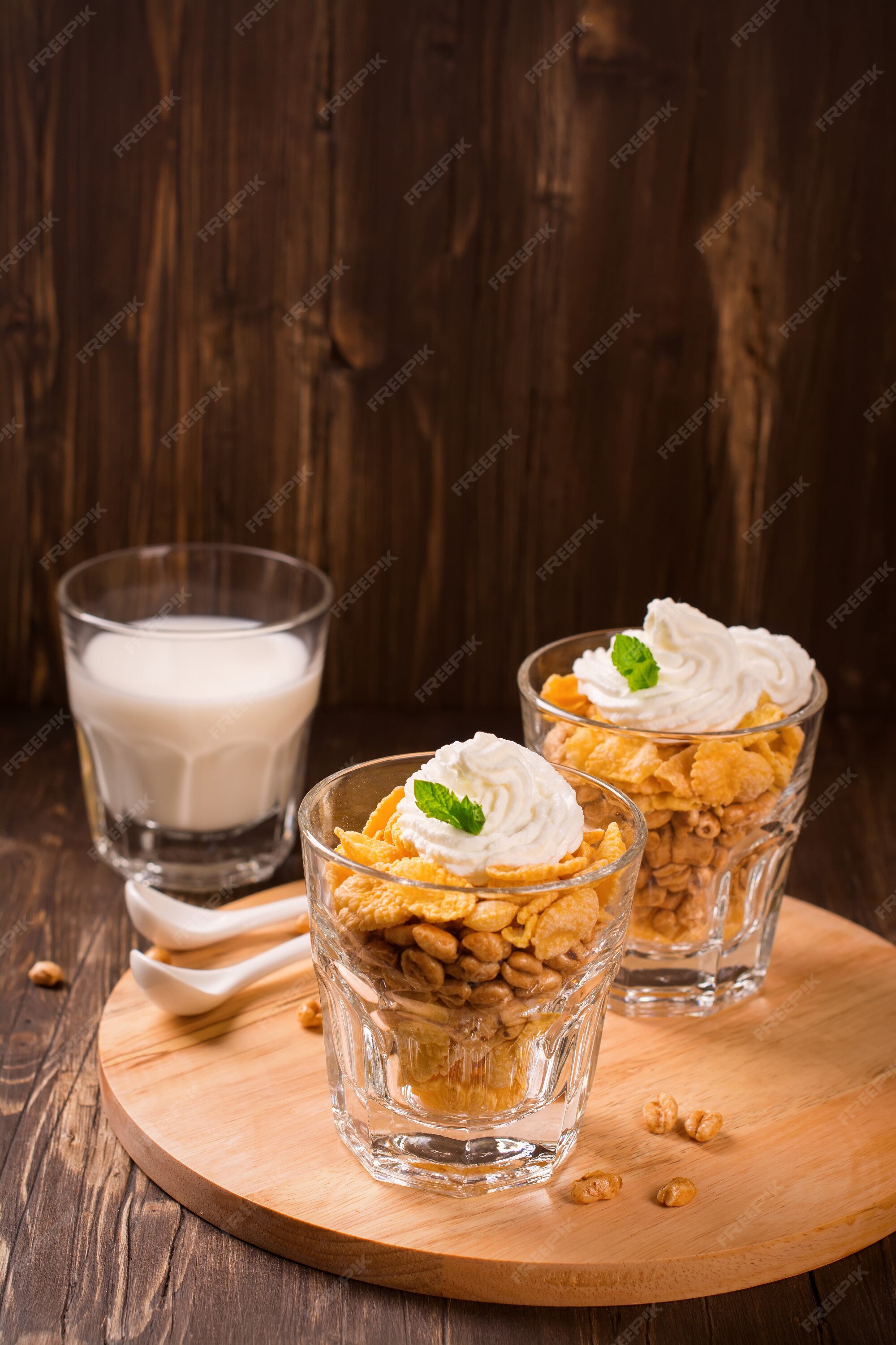Premium Photo Corn And Wheat Flakes In Glasses Served With Milk Cream And Mint On Wooden Table
