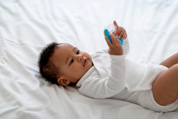Premium Photo | Cute Black Baby Holding Rattle Toy While Lying On Bed ... Premium Photo | Cute Black Baby Holding Rattle Toy While Lying On Bed ...