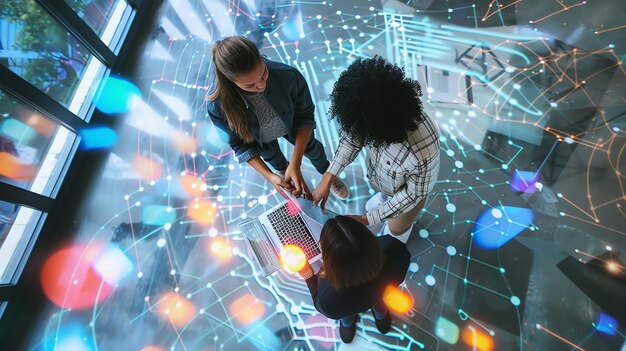 Diverse team of three young people stand together over a laptop in a ... Diverse team of three young people stand together over a laptop in a ...