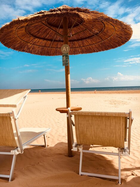 Premium Photo Empty Chairs And Thatched Roof At Beach Against Sky