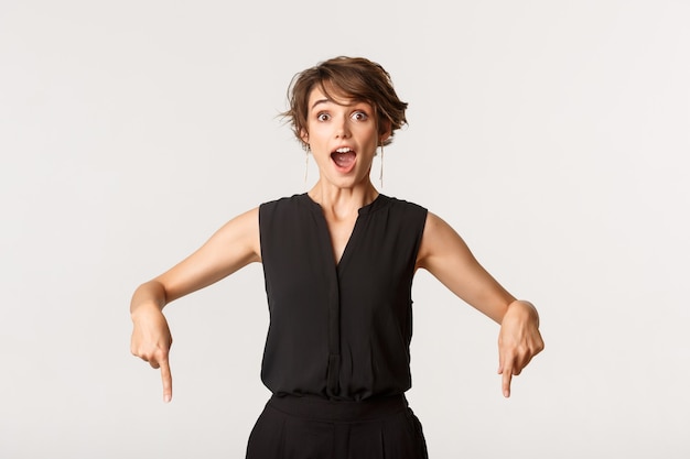 Premium Photo Excited And Impressed Brunette Girl Pointing Fingers Down