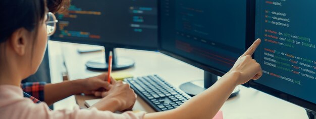 Female programer taking a note while young skilled web developer present program while computer ...