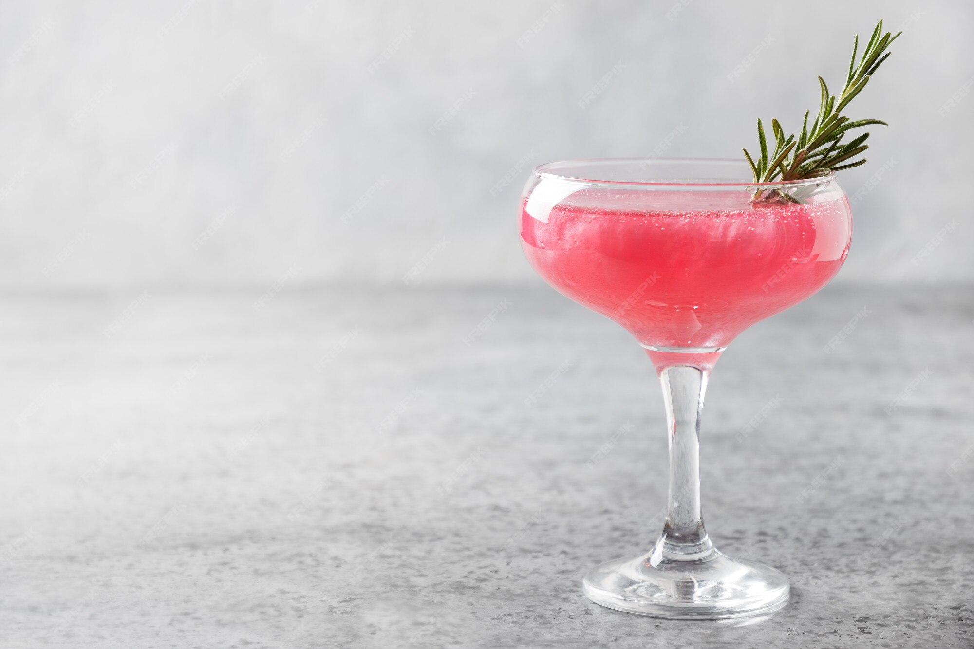 Premium Photo Glass Of Sparkling Rose Wine With Shimmer Edible Glitter Garnish Rosemary On Grey