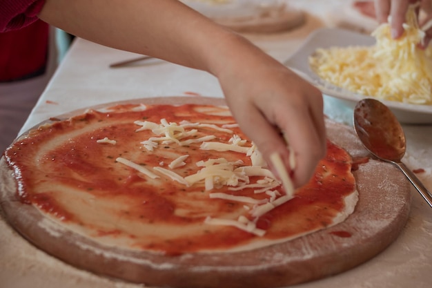 Premium Photo | Hand puts cheese on a row pizza on a wooden cutting ... Premium Photo | Hand puts cheese on a row pizza on a wooden cutting ...