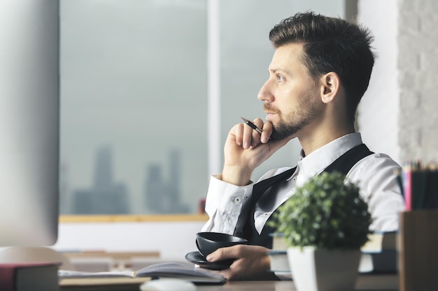 Premium Photo | Handsome guy drinking coffee at workplace Premium Photo | Handsome guy drinking coffee at workplace