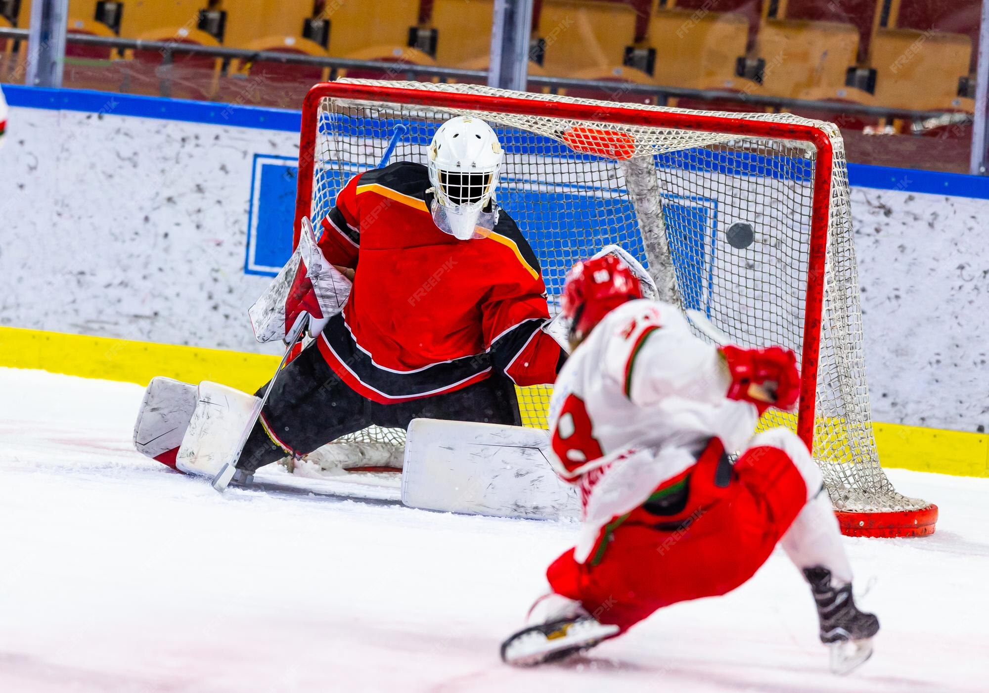 Premium Photo Ice Hockey Player Tries To Score With A Slap Shot And One Knee Down On The Ice
