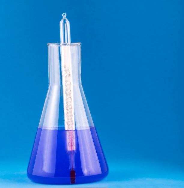 Premium Photo Laboratory Flask With Thermometer On Blue Background