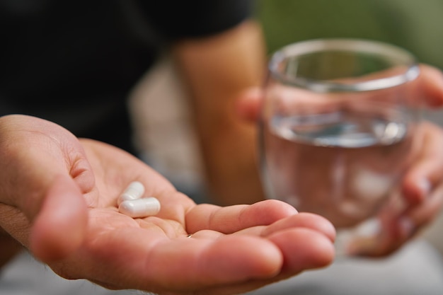 Man holding pills and glass of water at home person taking supplements ... Man holding pills and glass of water at home person taking supplements ...
