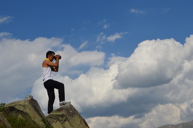 Premium Photo | Man standing on rocks looking through binoculars Premium Photo | Man standing on rocks looking through binoculars