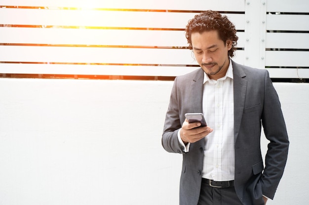 Premium Photo Mid Adult Businessman Using Mobile Phone Against Wall