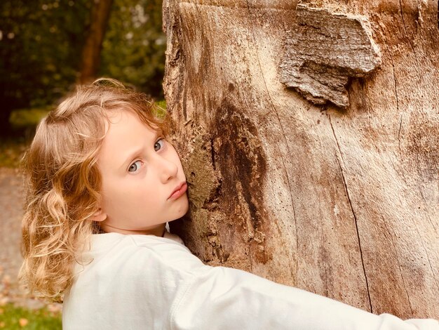 Premium Photo Portrait Of Cute Girl Embracing Tree Trunk