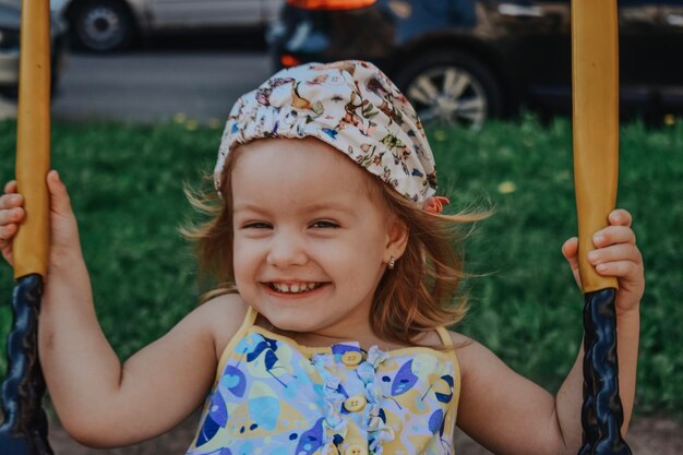 Premium Photo Portrait Of Cute Girl Smiling While Sitting On Swing In