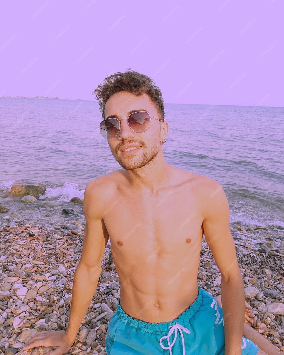 Premium Photo Portrait Of Shirtless Man Sitting At Beach