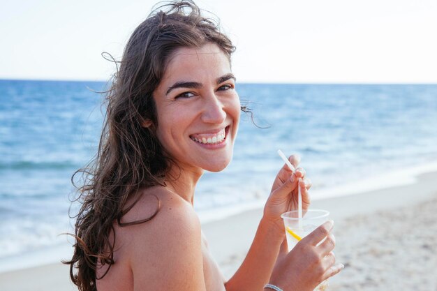 Premium Photo Portrait Of Smiling Woman Drinking Water From Beach