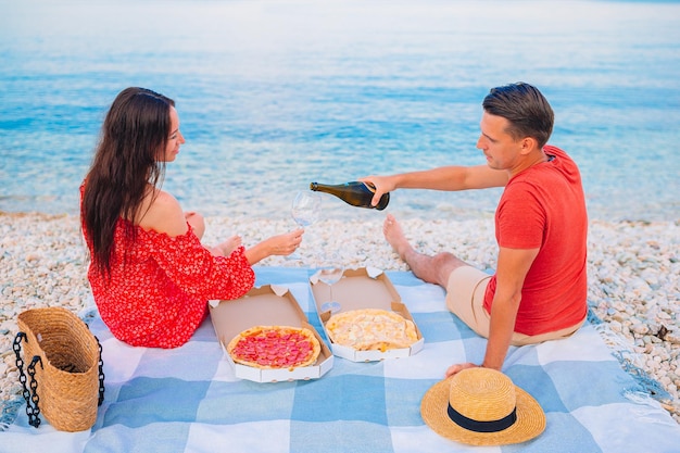 Premium Photo | Rear view of couple enjoying while sitting at beach Premium Photo | Rear view of couple enjoying while sitting at beach