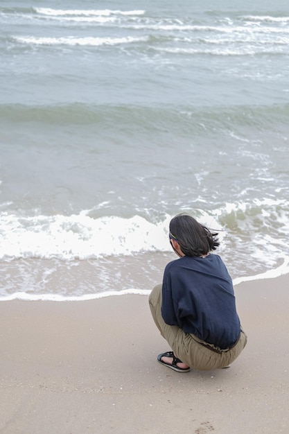 Premium Photo Rear View Of Girl Crouching At Sandy Beach