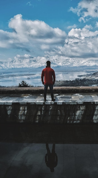 Premium Photo Rear View Of Man Standing At Lakeshore Against Cloudy Sky