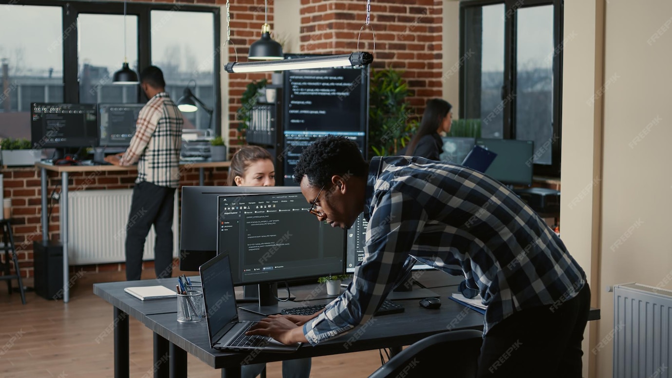 Premium Photo | Senior developer coding on laptop at desk with computer screens parsing code in ...