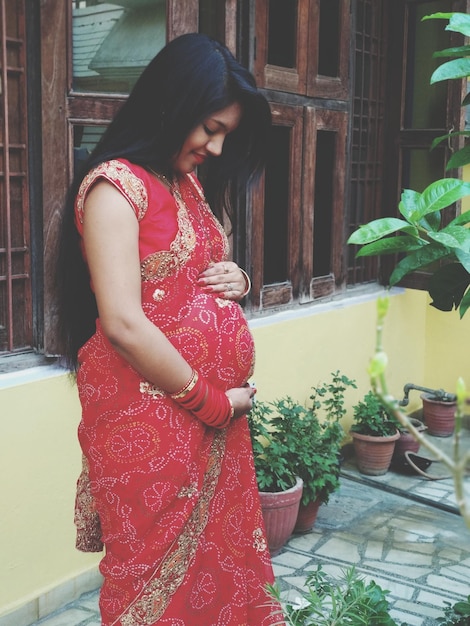 Premium Photo Side View Of Pregnant Woman Standing By Potted Plants