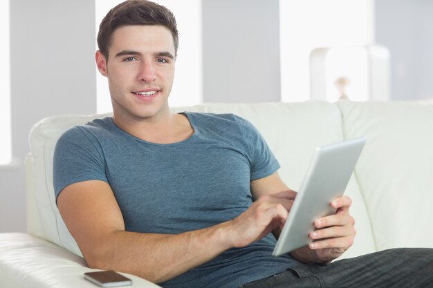 Premium Photo | Smiling handsome man relaxing on couch using tablet Premium Photo | Smiling handsome man relaxing on couch using tablet