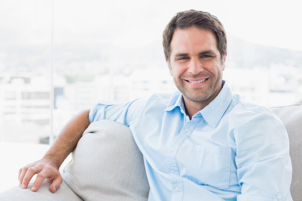Premium Photo | Smiling handsome man sitting on the couch looking at camera Premium Photo | Smiling handsome man sitting on the couch looking at camera