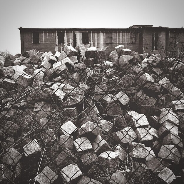 Premium Photo | Stack of stones by old built structure seen through fence Premium Photo | Stack of stones by old built structure seen through fence