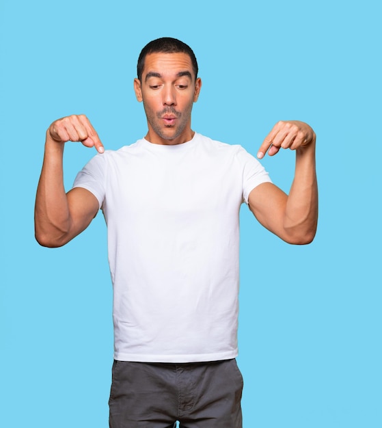 Premium Photo | Surprised young man pointing down Premium Photo | Surprised young man pointing down
