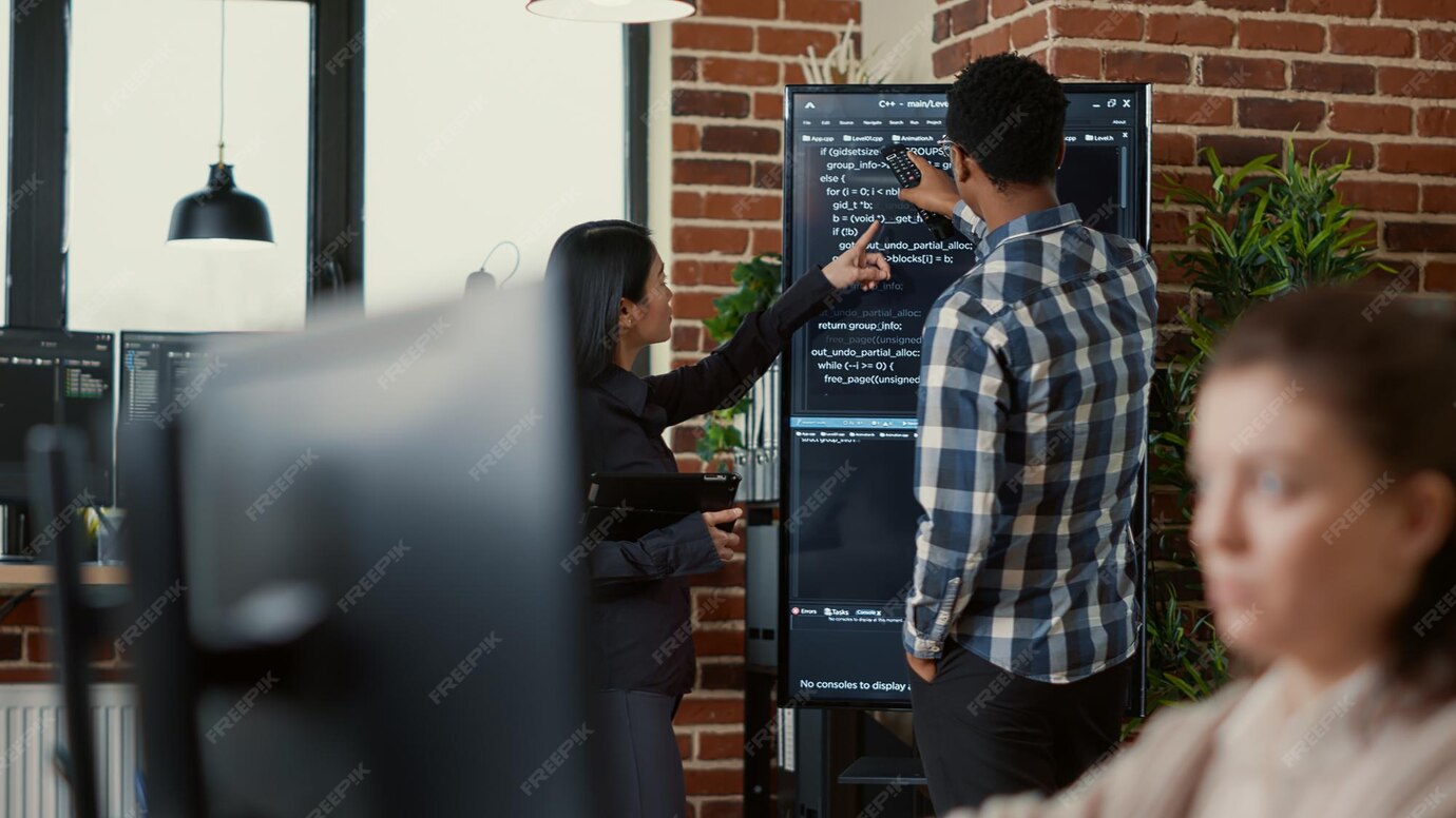 Premium Photo | System developers analyzing code on wall screen tv looking for errors comparing ...