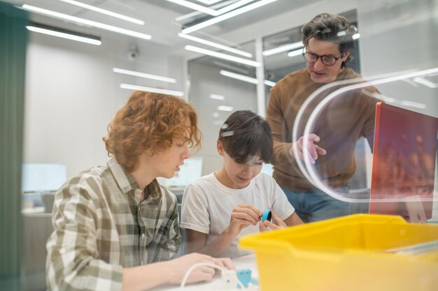 Premium Photo | Teacher in eyeglasses explaining something to his students Premium Photo | Teacher in eyeglasses explaining something to his students