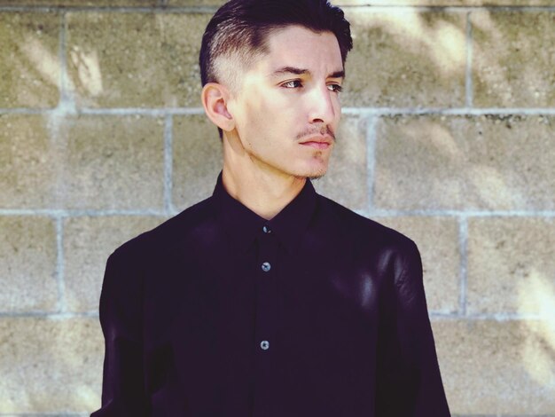 Premium Photo | Thoughtful young man standing against wall Premium Photo | Thoughtful young man standing against wall