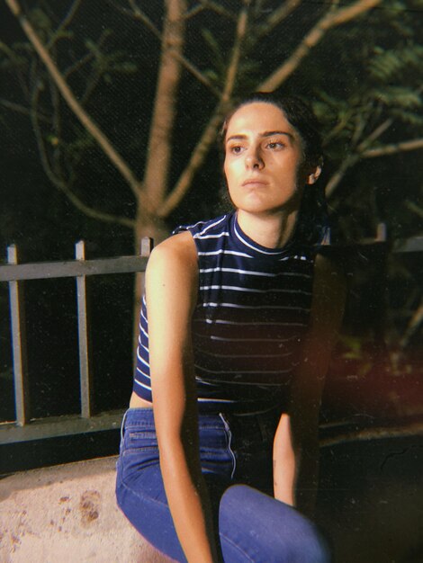 Premium Photo Thoughtful Young Woman Sitting On Railing At Night