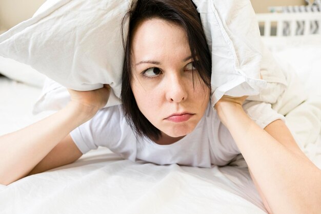 Premium Photo | Troubled woman in bed covering ears to shut out noise Premium Photo | Troubled woman in bed covering ears to shut out noise