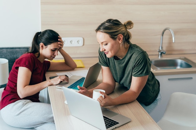 Premium Photo Two Female Coworkers Working Using Laptops In The Kitchen