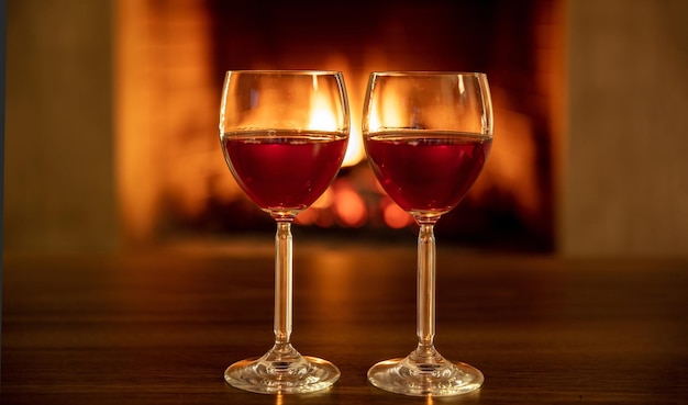Premium Photo Two Red Wine Glasses Burning Fireplace Background Couple Drinking Valentines Day