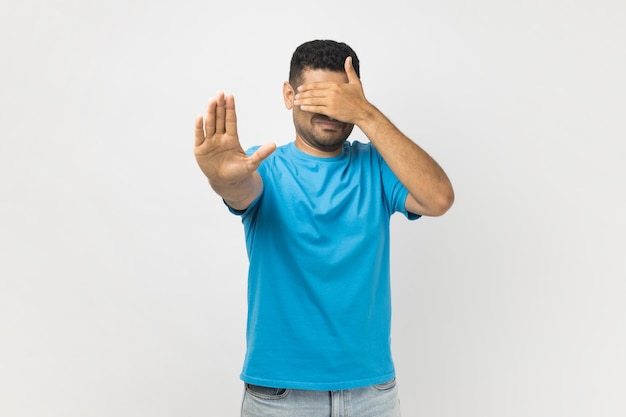Premium Photo Unshaven Man In T Shirt Standing Covering His Face With Hand Hiding His Face