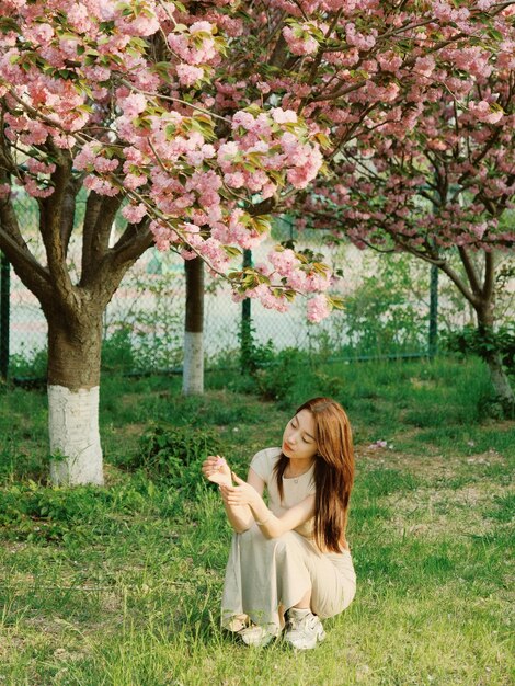 Premium Photo A Woman Sitting In The Grass Next To A Tree