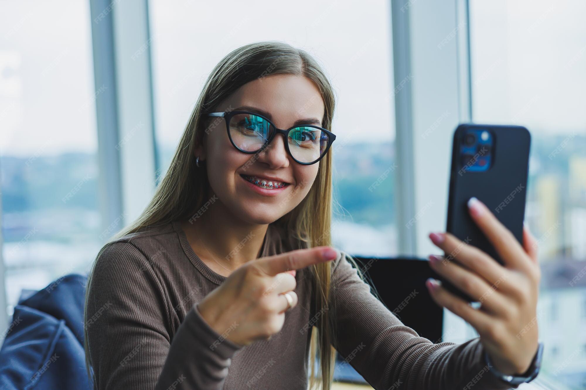 Premium Photo Young Smiling Woman Wearing Glasses In Casual Clothes Sitting In A Chair By The