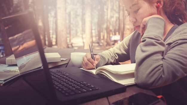Premium Photo | Young woman writing while using laptop in forest Premium Photo | Young woman writing while using laptop in forest